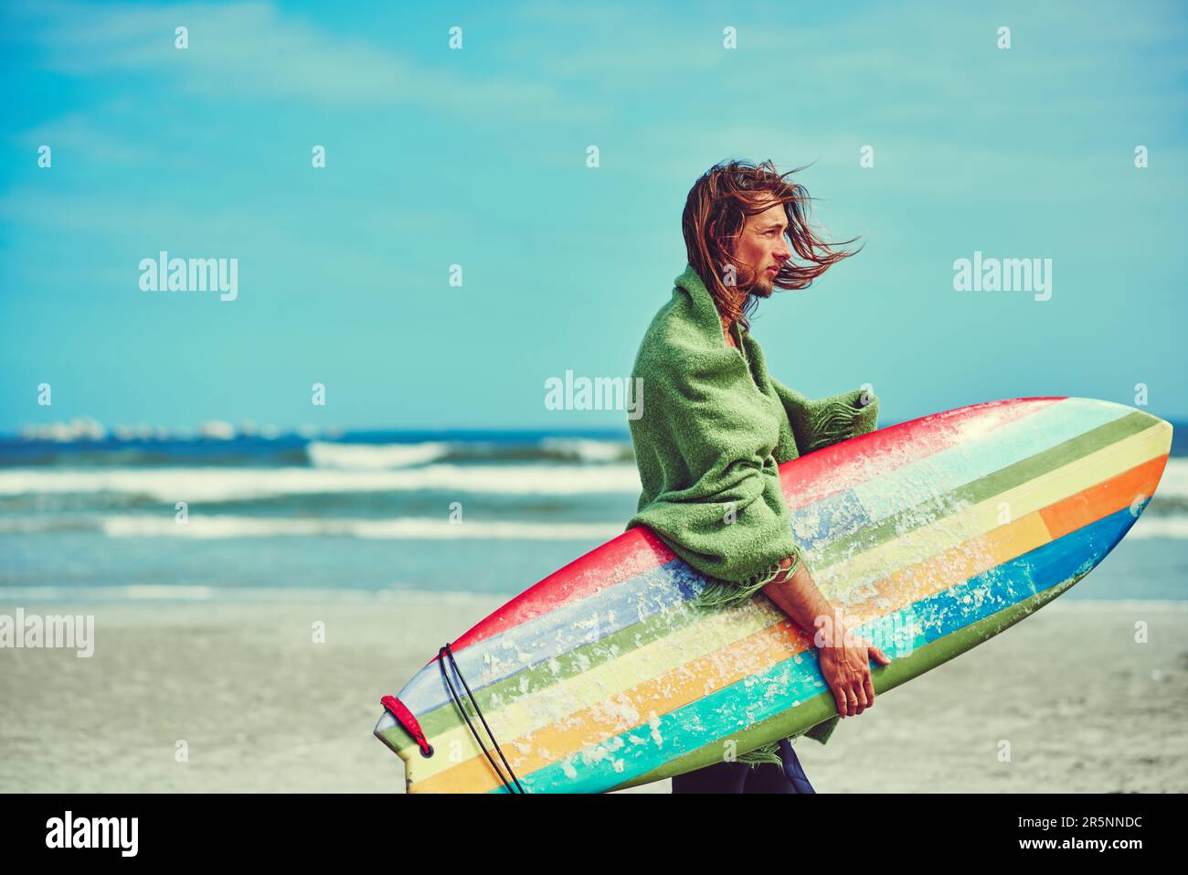 I wont miss a wave today. a young surfer strolling on the beach with ...