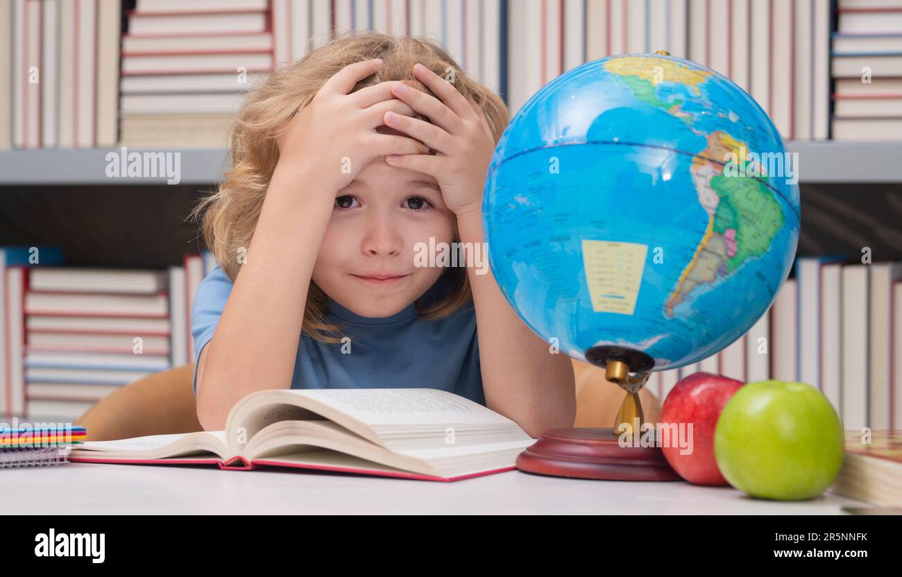 Tired and bored pupil. School kid looking at globe in library at the ...