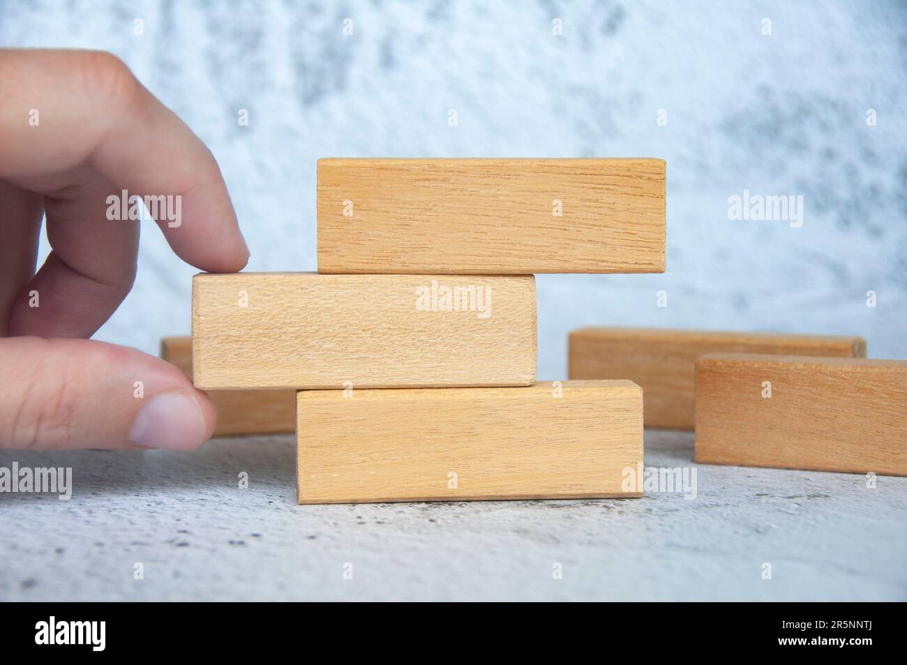 Hand pulling wooden block from other stacked wooden block with ...