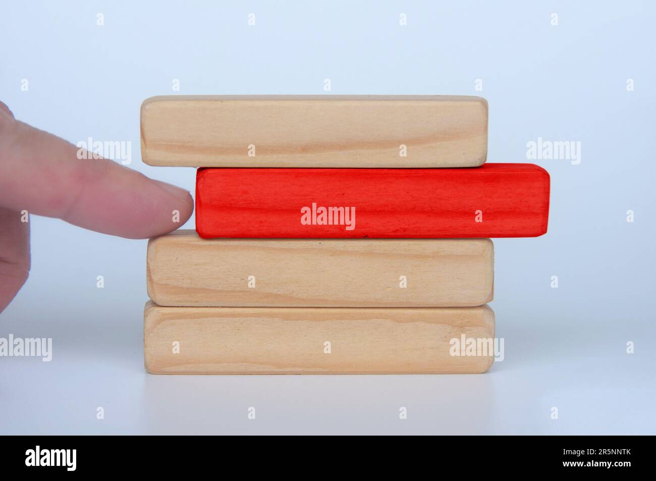 Hand pushing red wooden block from other stacked wooden block ...