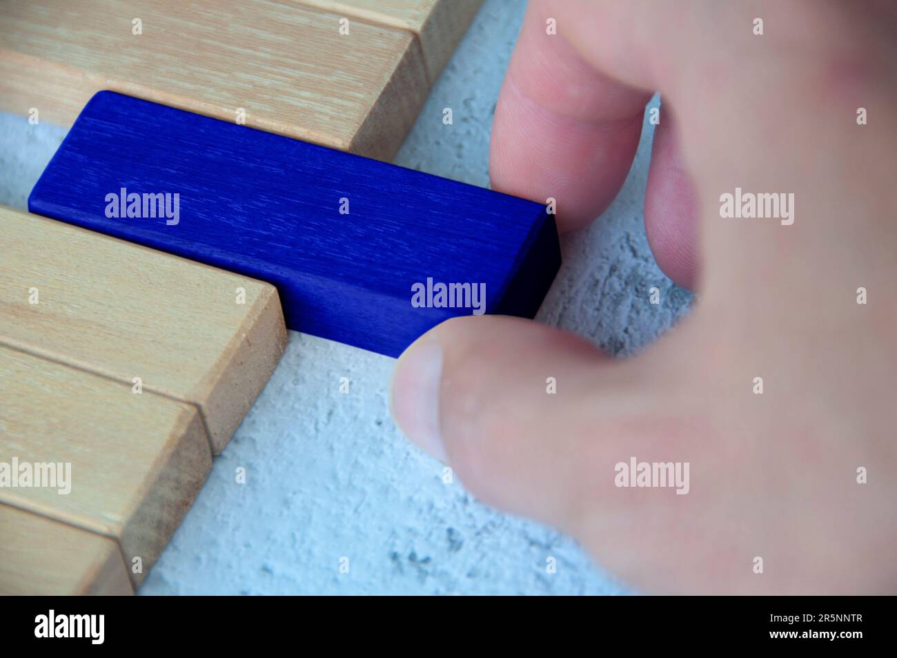 Hand pulling blue wooden block from other wooden block with ...