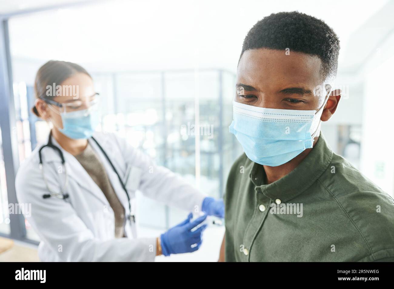 I cant look. a young doctor giving a patient an injection in an office ...