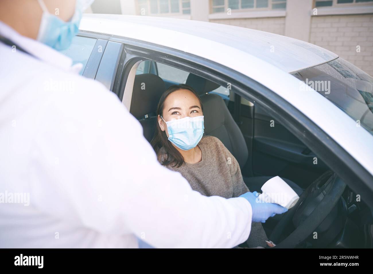 No fever, no problem. a masked young woman getting her temperature ...