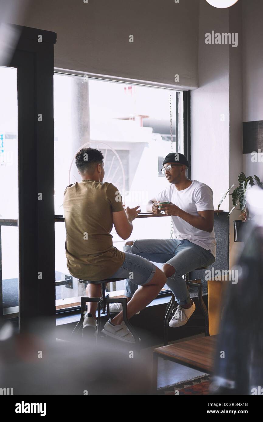 Getting to know one another over coffee. two young men talking while ...