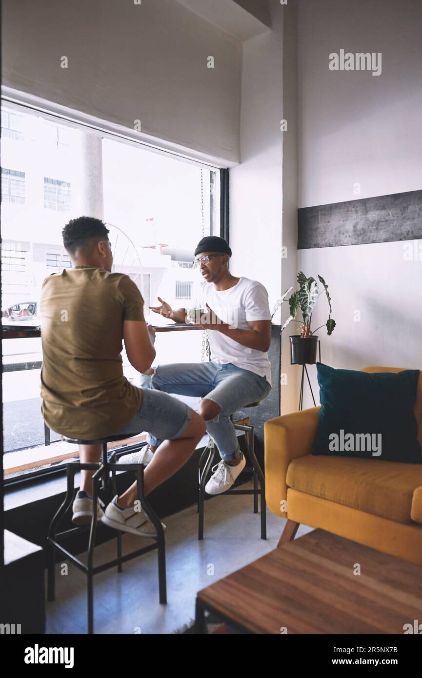 Talking about it always helps. two young men talking while having coffee together in a cafe ...