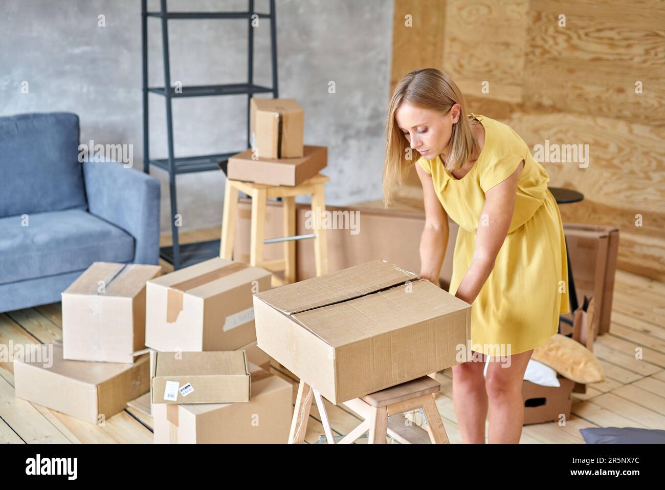 Young girl packing plates into the boxes ready to move. Woman unpacking ...