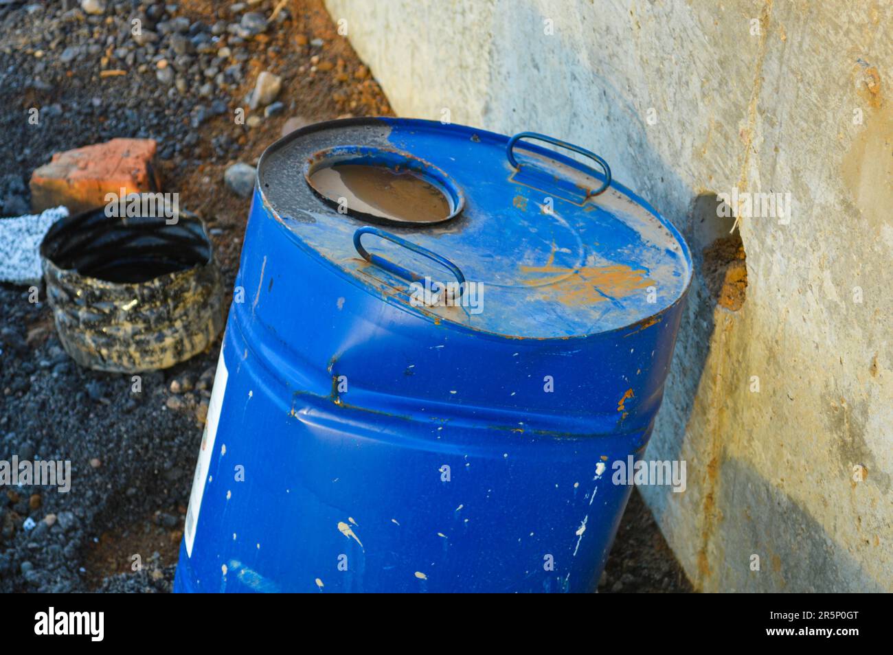 a bright blue barrel stands on the road. a flammable liquid is poured ...