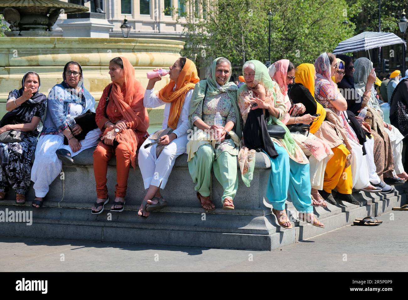 London, UK. Sikh women in colourful clothing sit by the Trafalgar ...