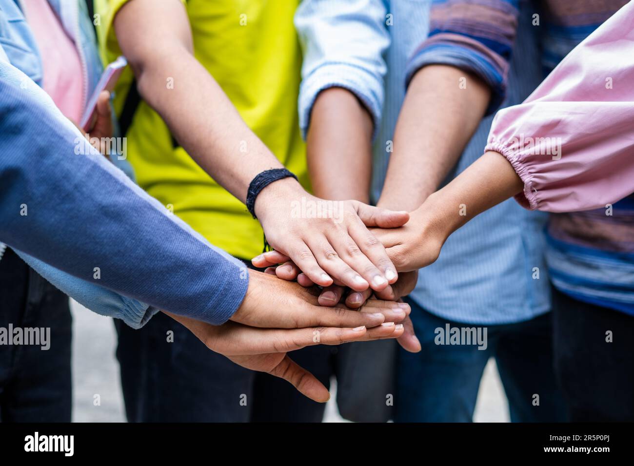 Close up shot group of students joining hands at college campus for ...