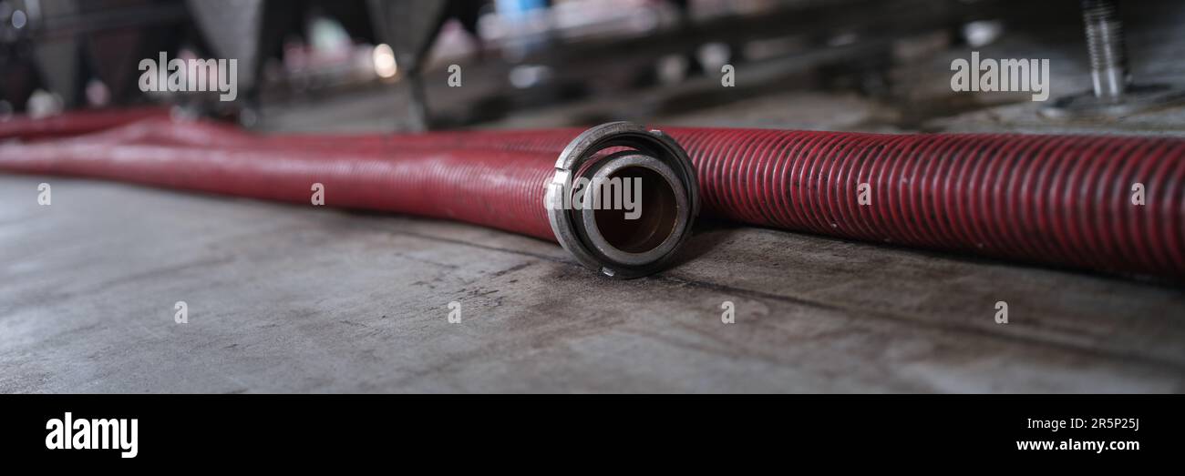 Red rubber hose lies on floor in industrial factory. Various mechanisms ...