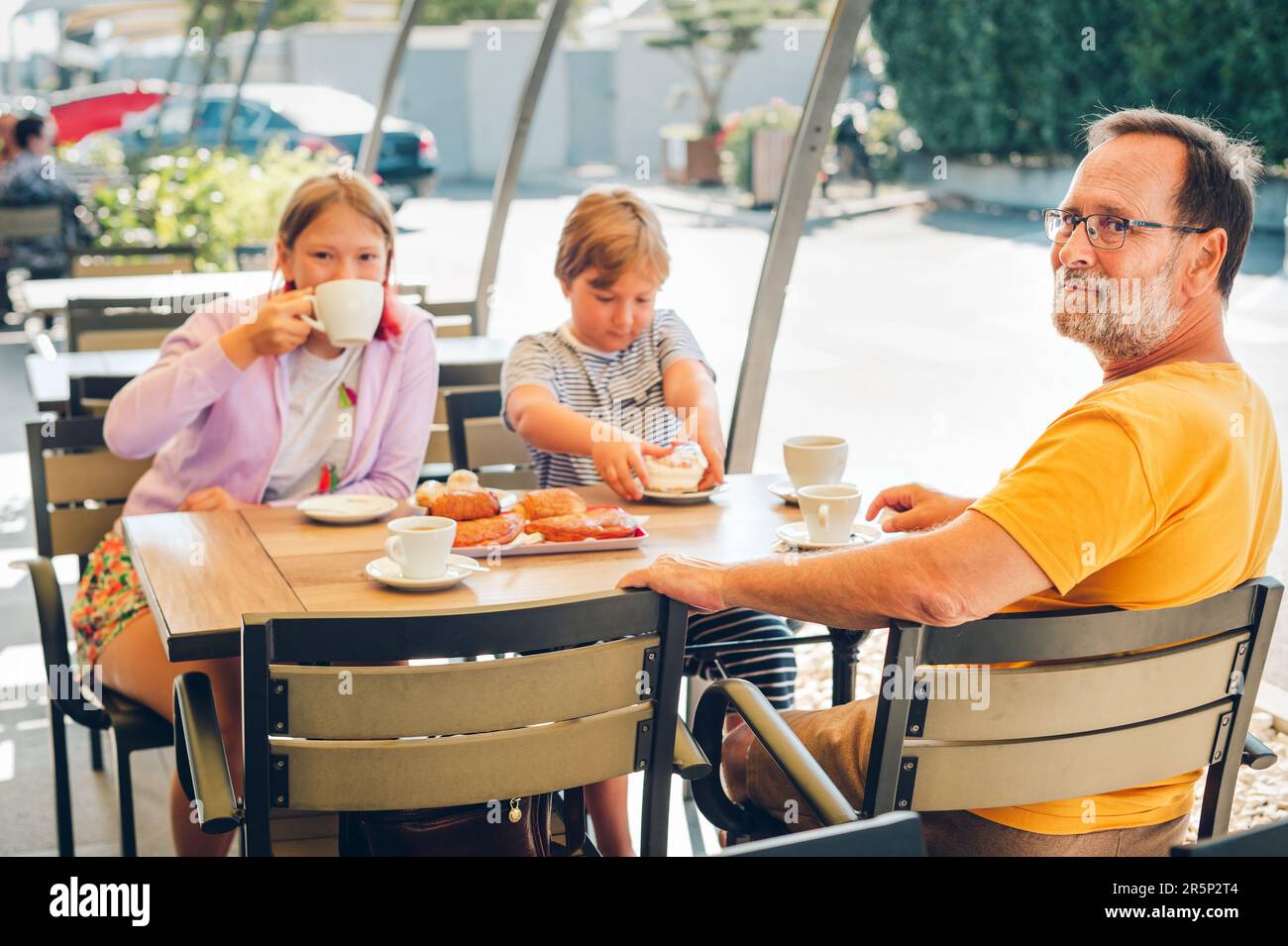 Family with kids having breakfast in outdoor cafe or restaurant ...