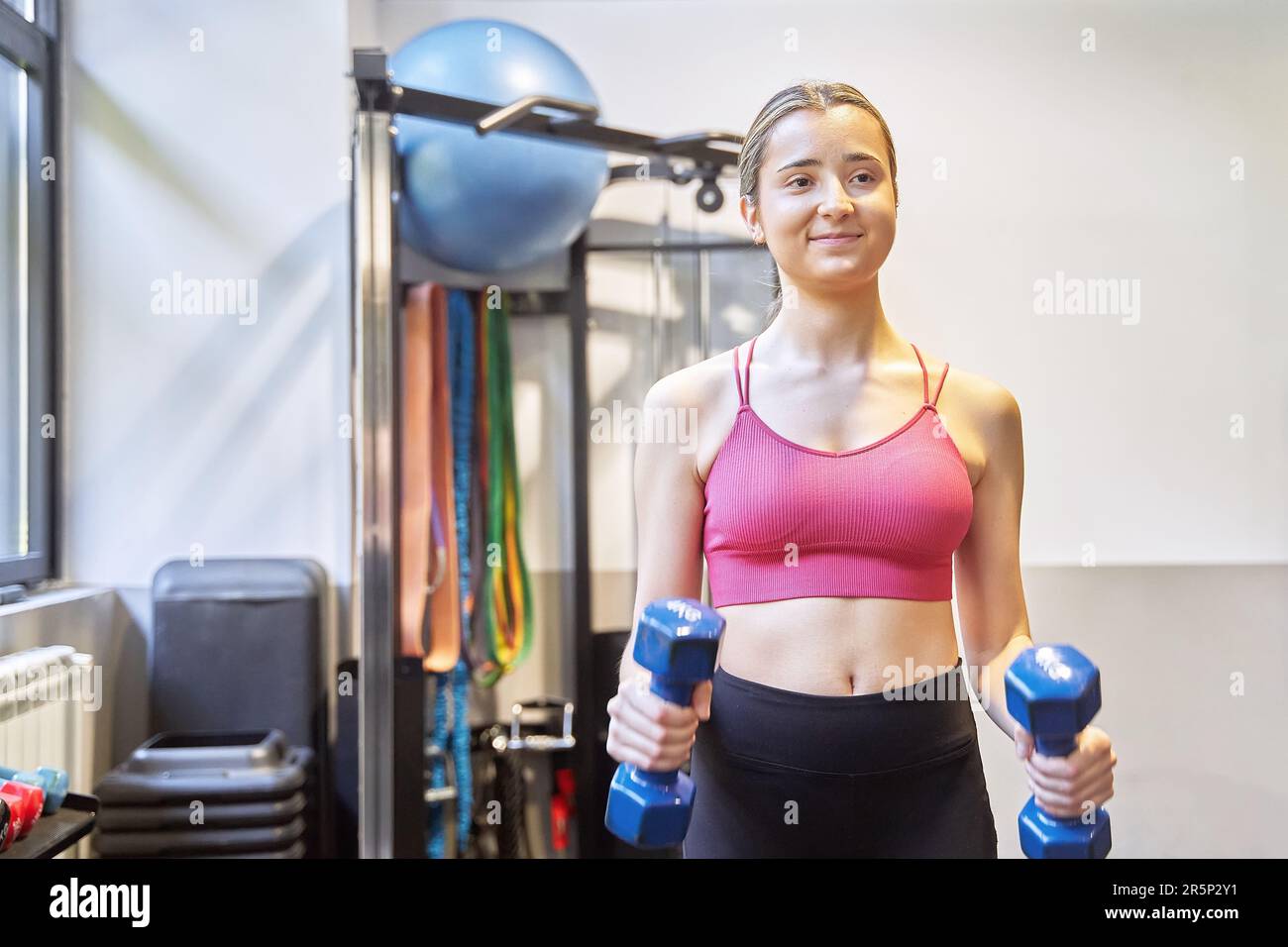 Blonde Girl Engaging in Arm Exercises with Dumbbells at the Gym for ...