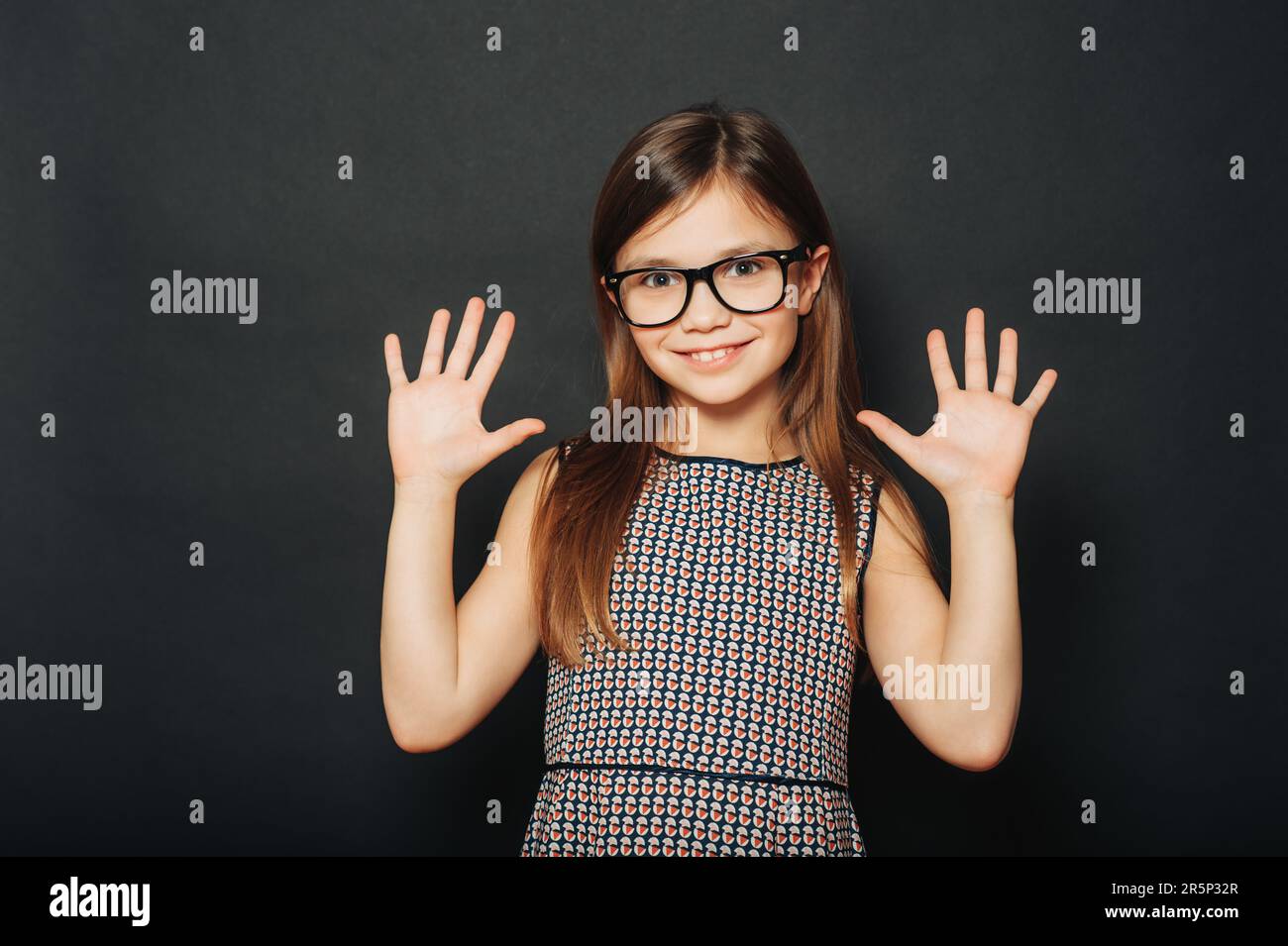 Studio portrait of pretty little girl, wearing eyeglasses, posing on ...