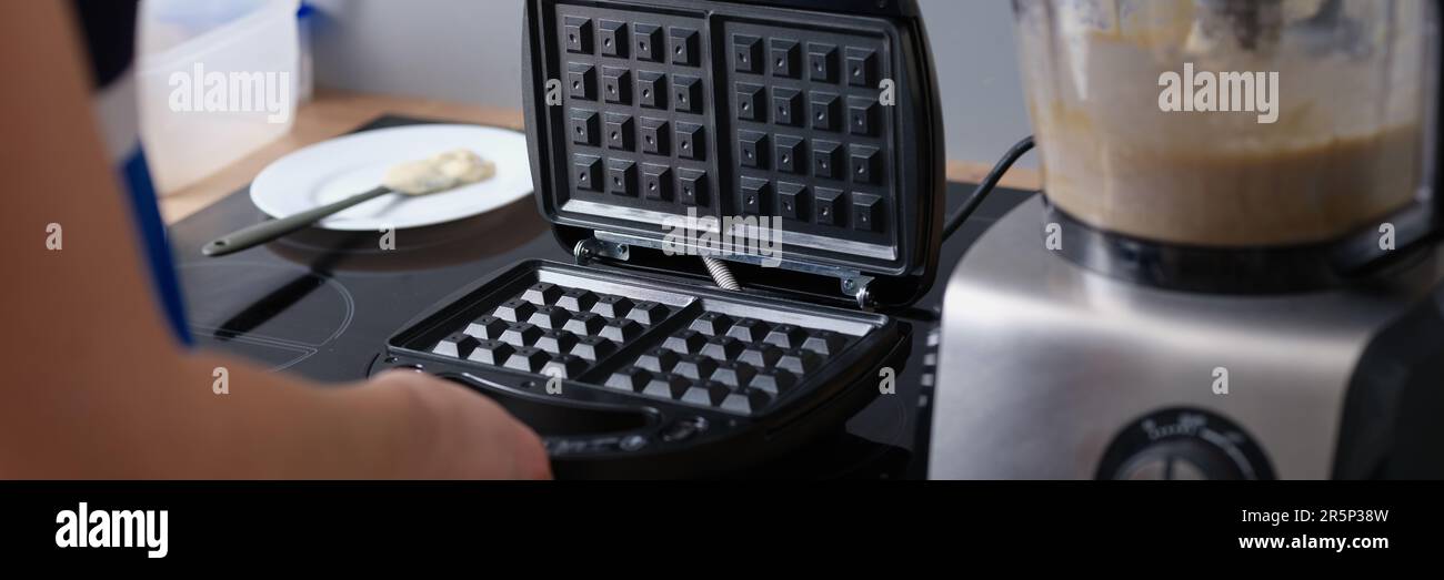 Woman opens waffle iron to make waffles in kitchen Stock Photo - Alamy