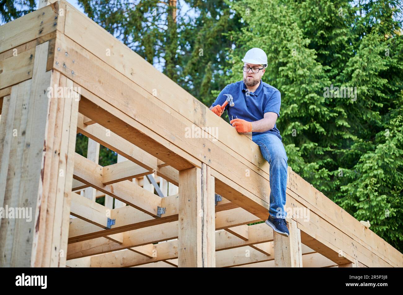 Carpenter constructing double-story wooden-framed house beside the ...