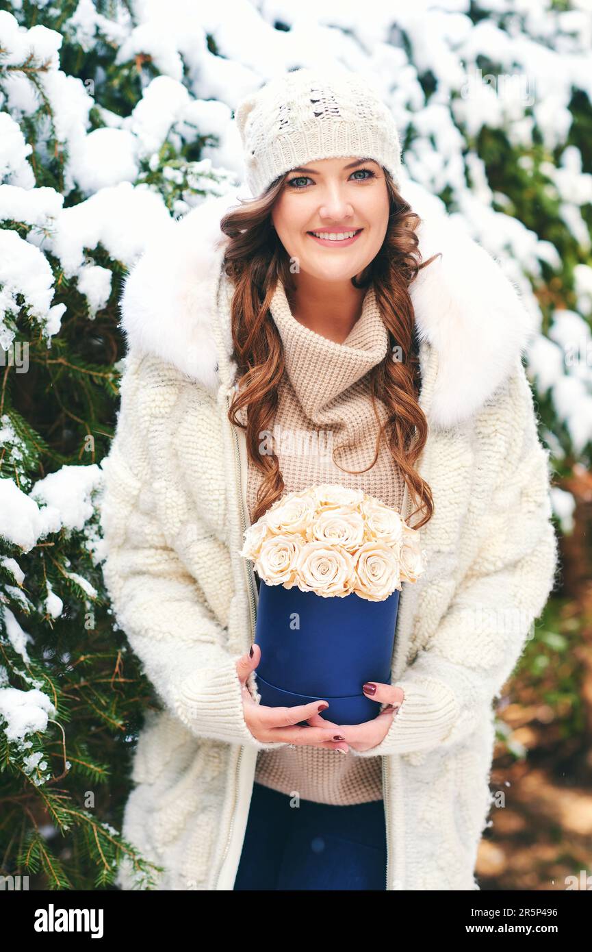 Outdoor portrait of beautiful woman holding box with golden roses ...