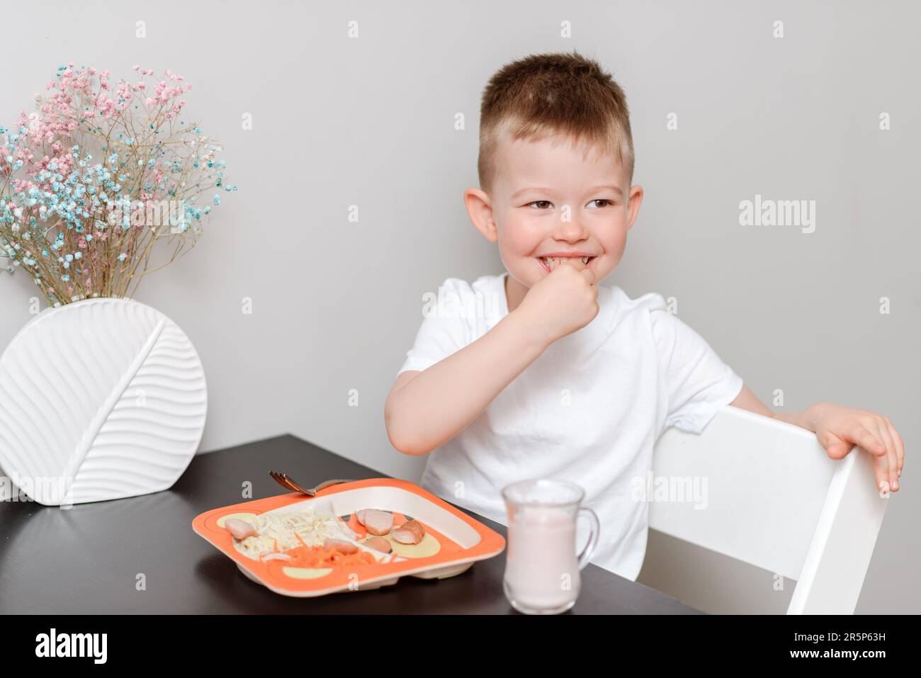Cute boy eating delicious pasta at the table in the kitchen Stock Photo ...