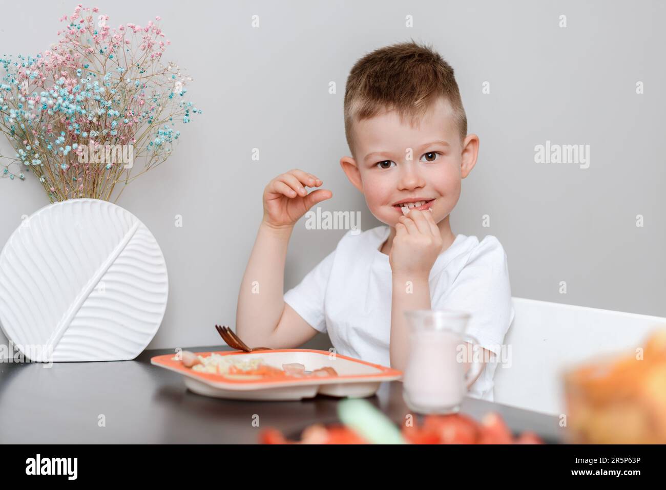 Cute boy eating delicious pasta at the table in the kitchen Stock Photo ...