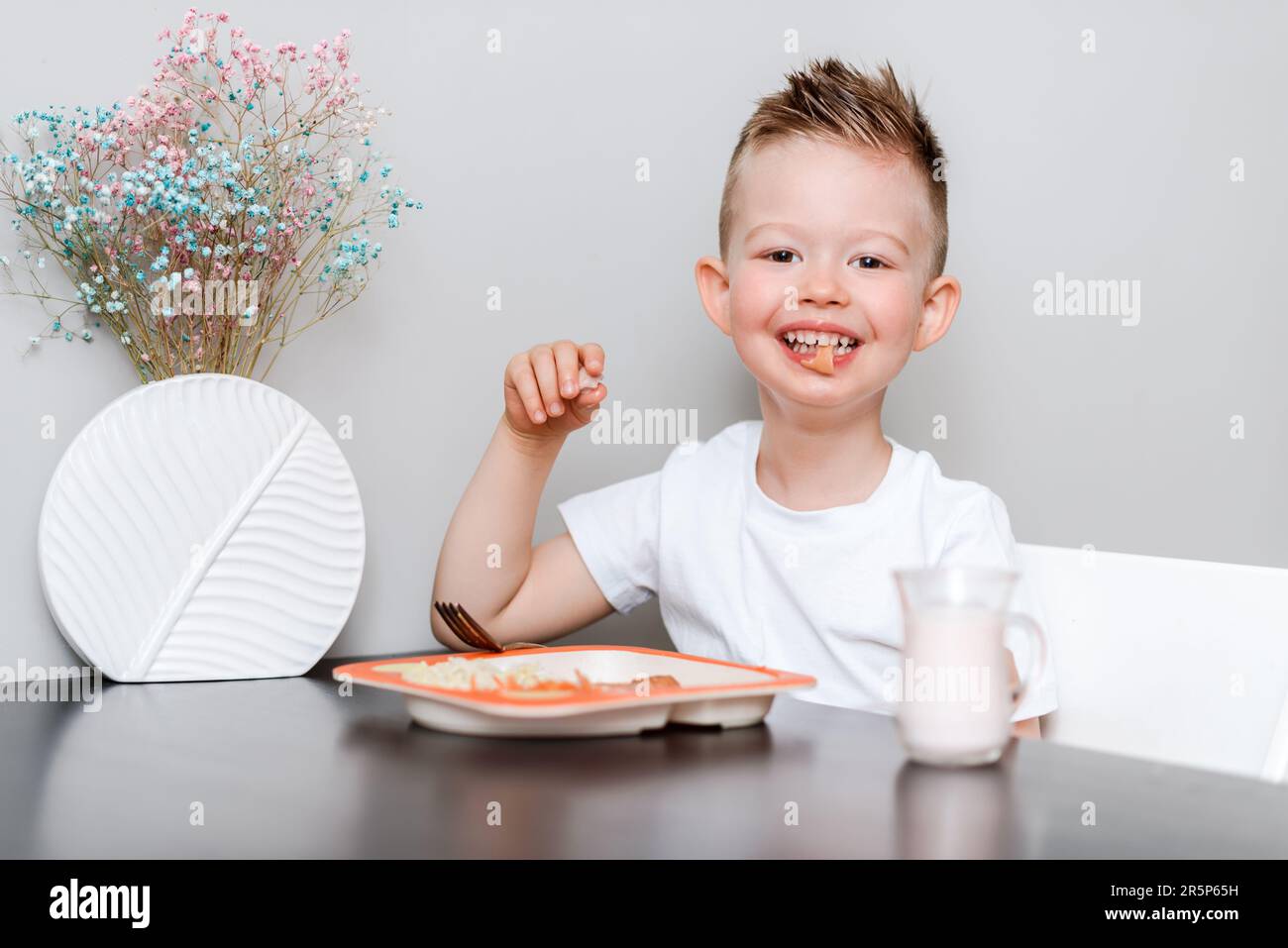 Cute boy eating delicious pasta at the table in the kitchen Stock Photo ...