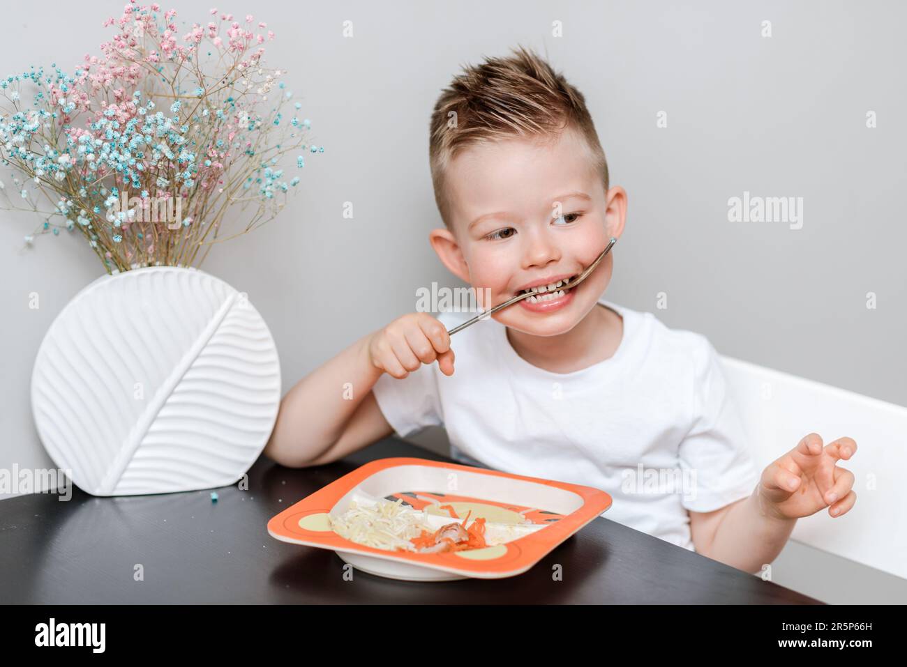 Happy child eating pasta at the table in the kitchen Stock Photo - Alamy