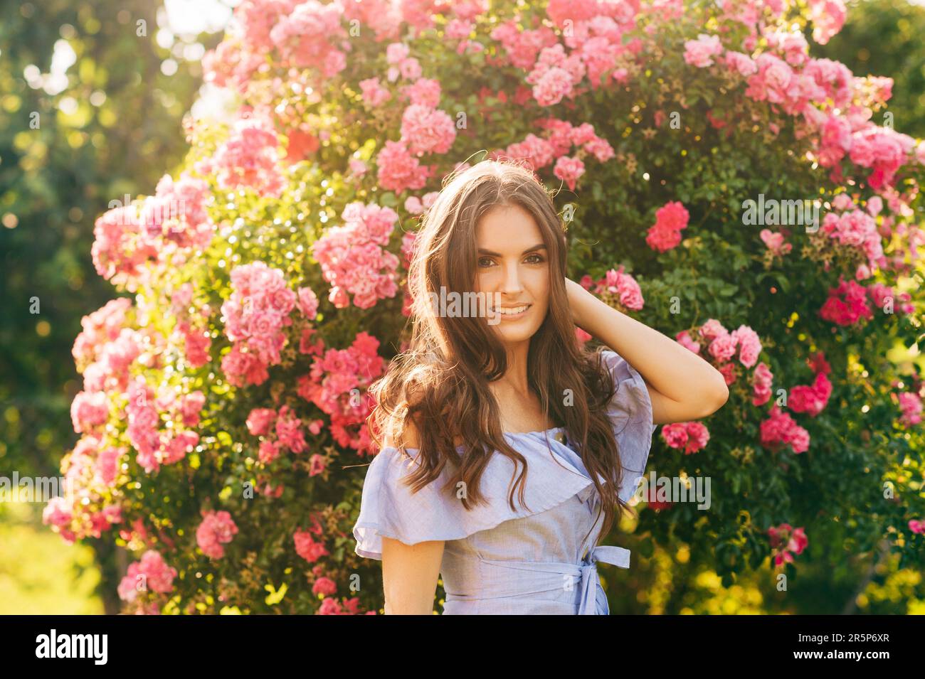 Outdoor portrait of pretty young woman posing in summer garden with ...