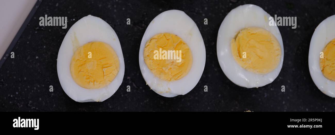 Hard boiled eggs cut in half on black background Stock Photo - Alamy