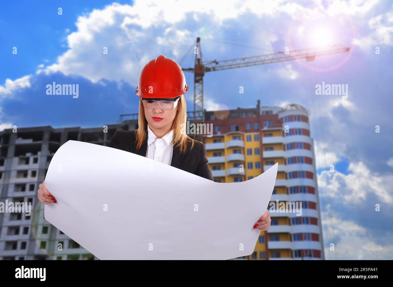 Woman engineer holding blueprint and standing on buildings background ...