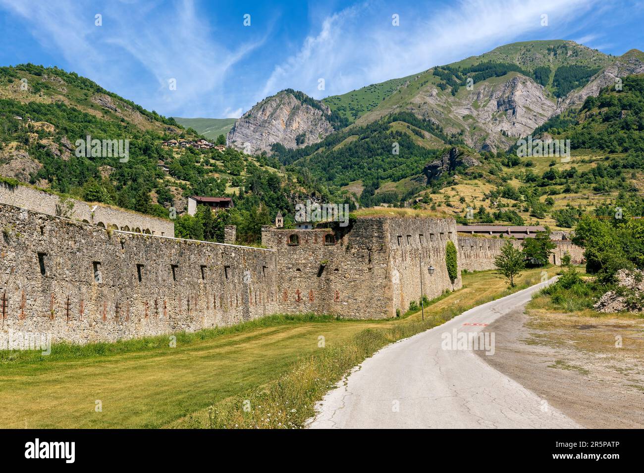 View of narrow road along old military fort as mountains under blue sky ...