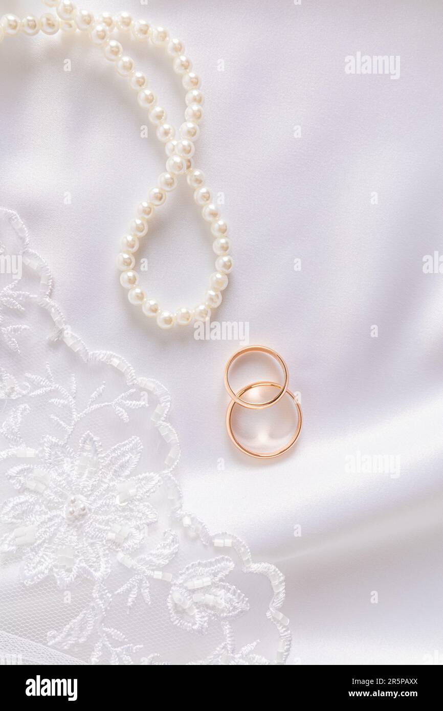 Vertical view of two gold wedding rings, part of the lace of the bride ...