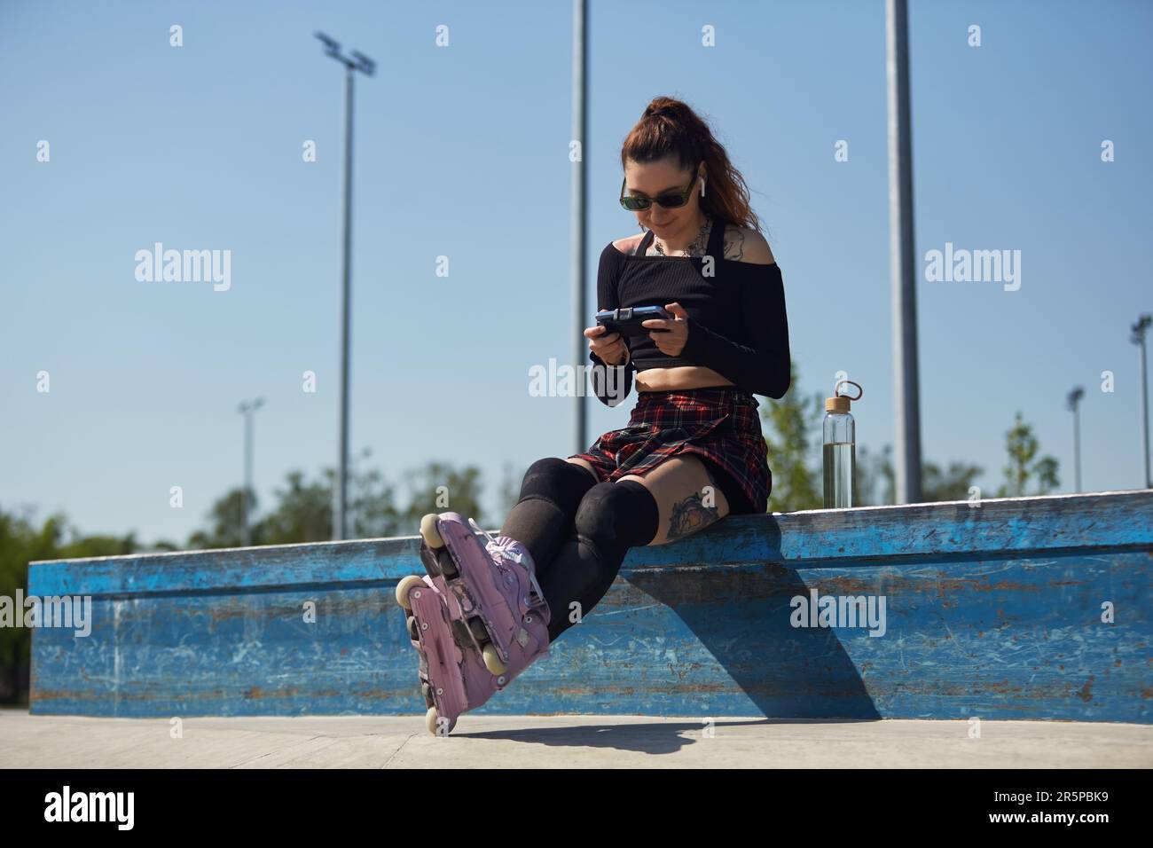 Cool young skater playing mobile game on a smart phone in a skatepark ...