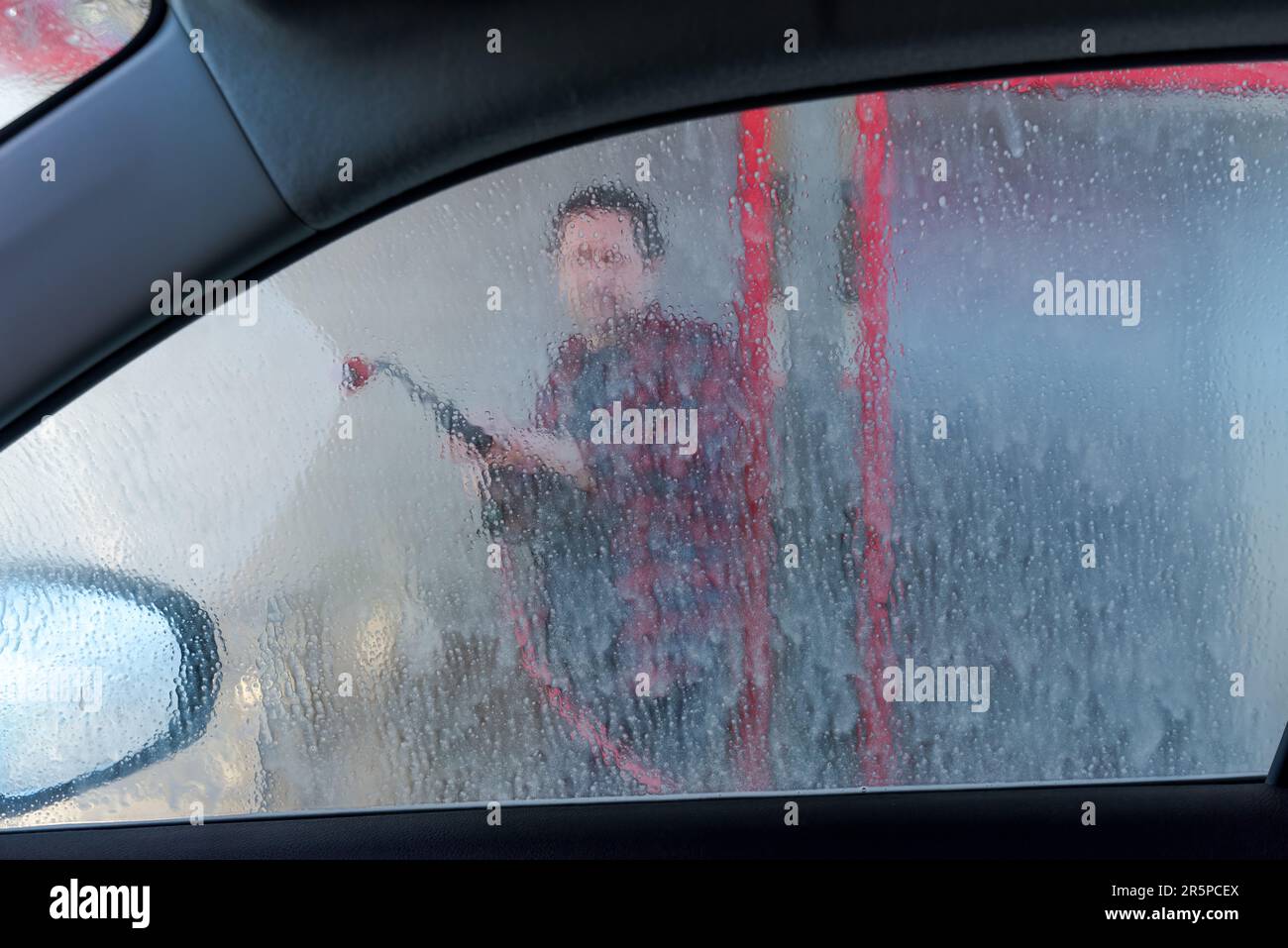 Man washing car with water gun in carwash self-service. Soap sud, wax ...