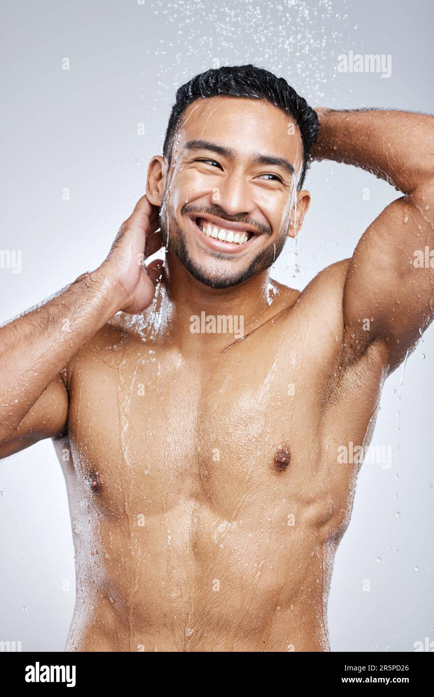 Man in shower with smile, cleaning and studio background for hygiene with shampoo, healthy body ...