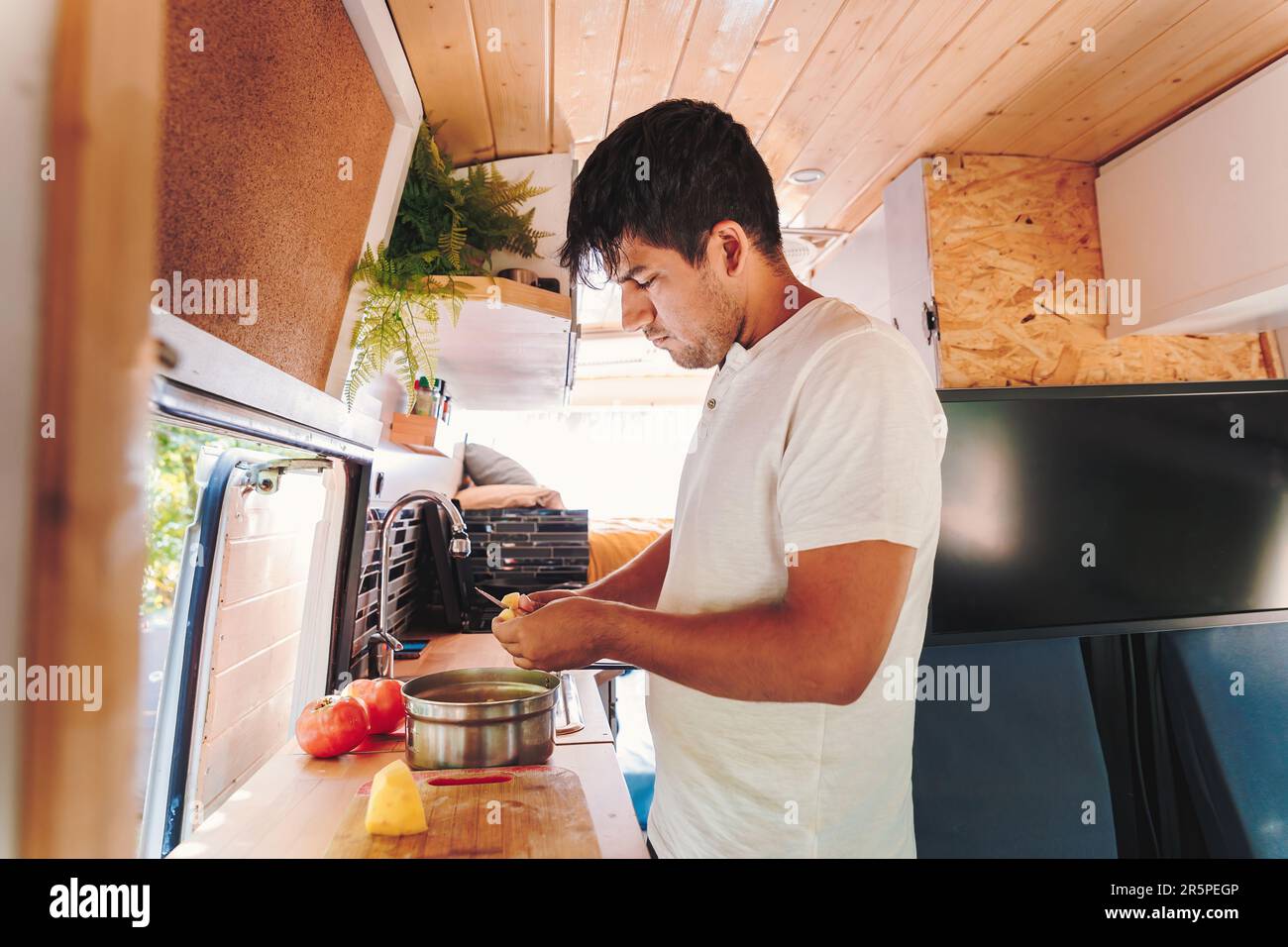 Man preparing food for cooking in the kitchen of his handmade camper ...