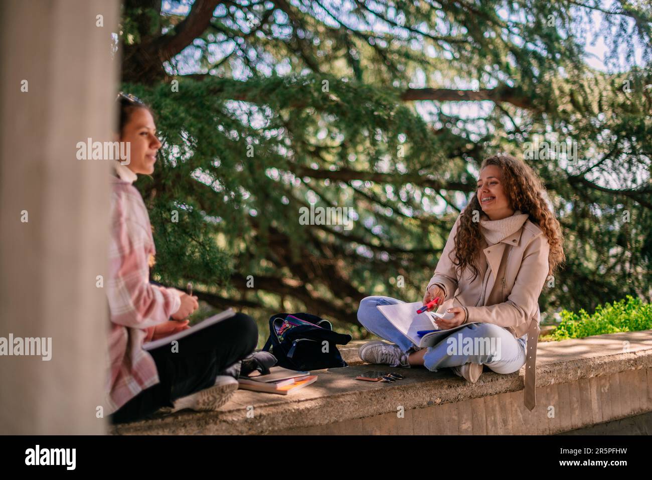 Beautiful girls writing homework after school. They are smiling while ...