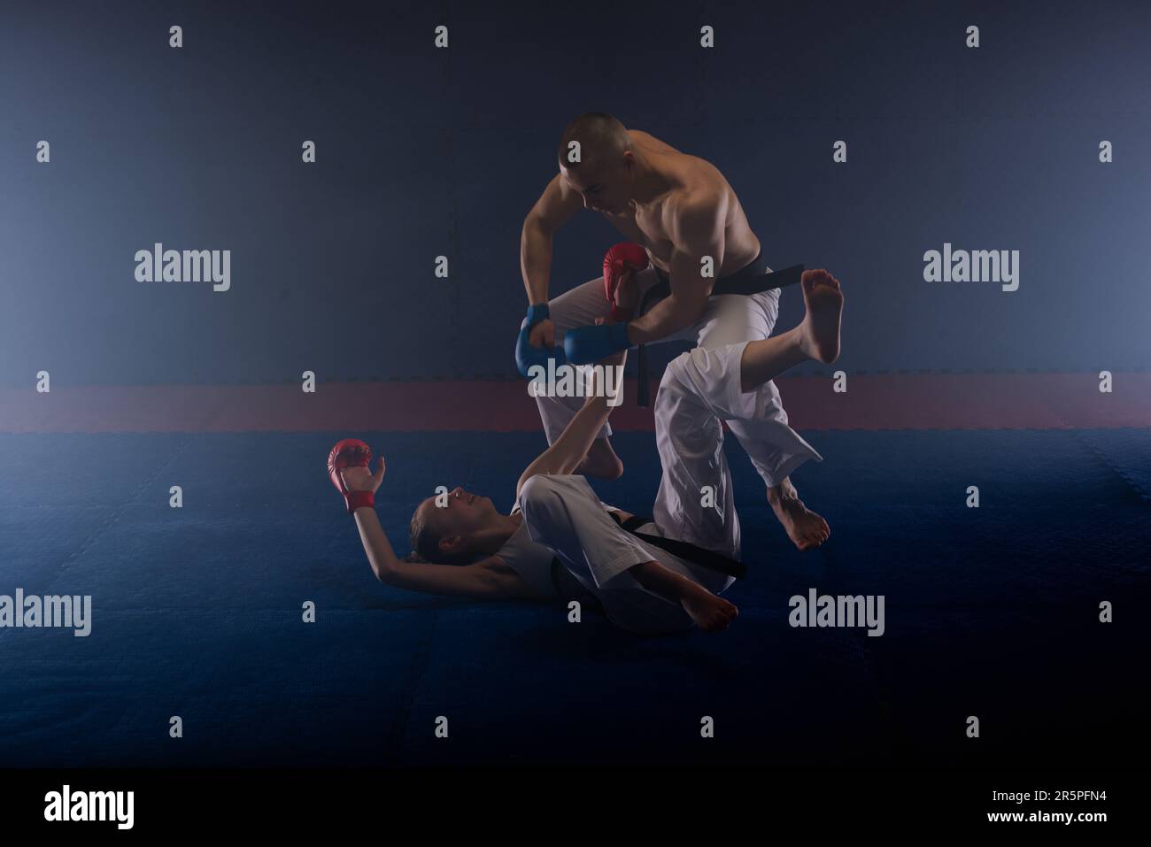 Two young and strong karate people fighting on the floor at the karate ...