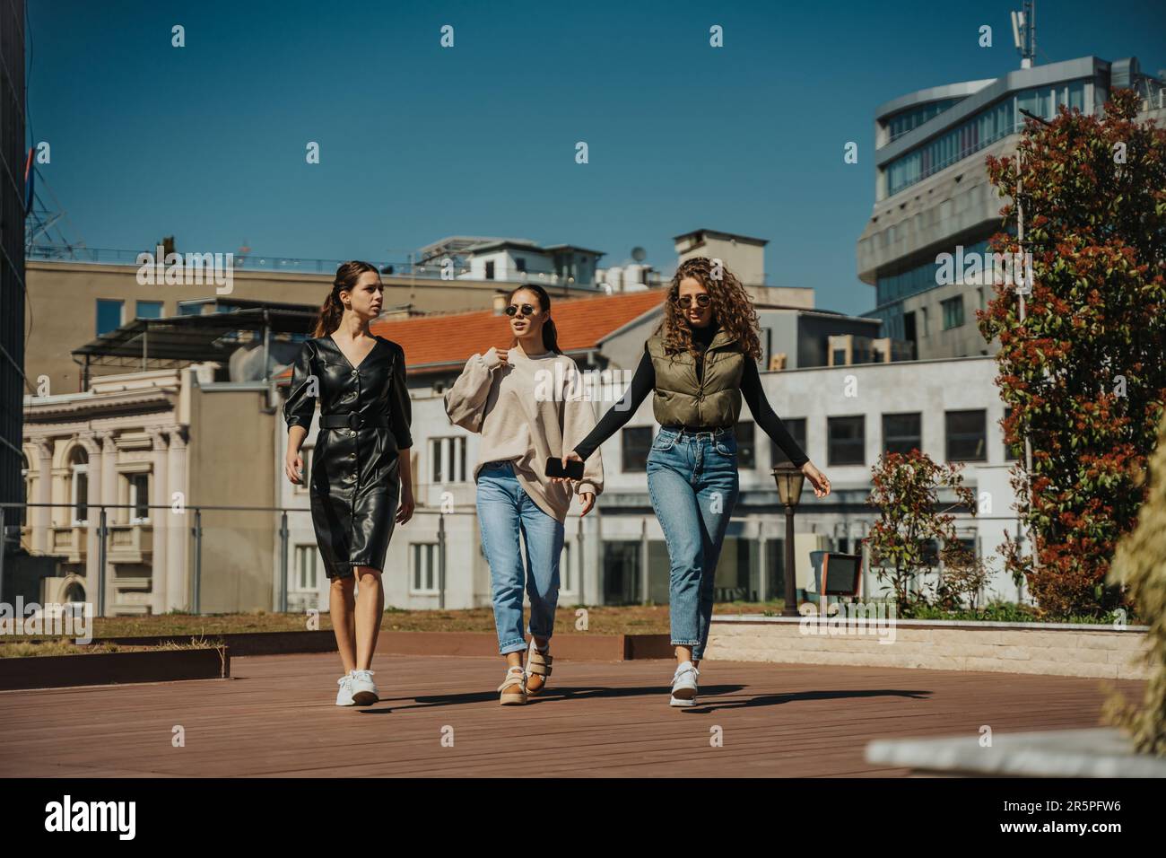 Three girls hanging out in the city. Curly haired girl dancing while ...