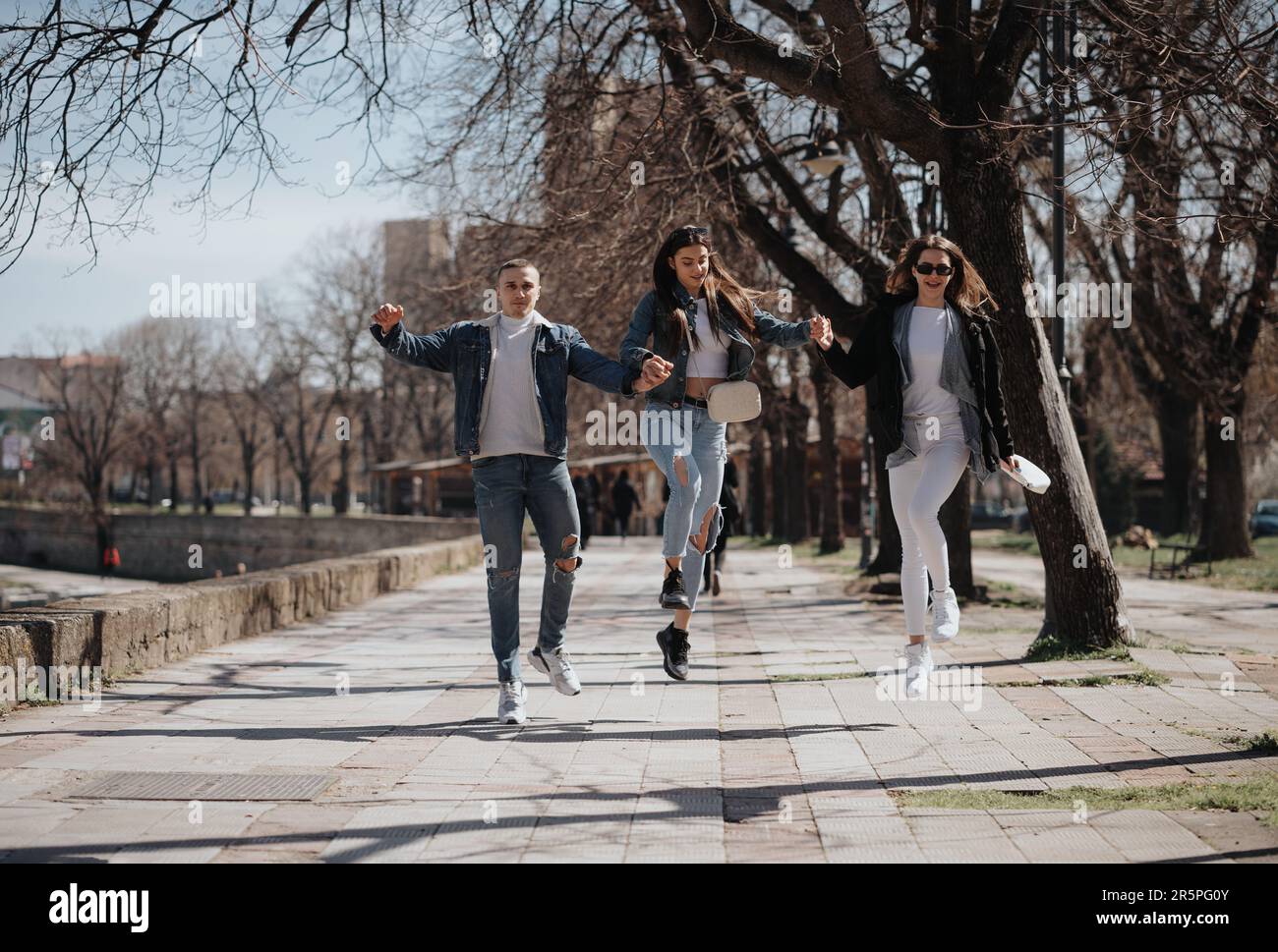 Three close friends having fun while jumping and walking at the park ...