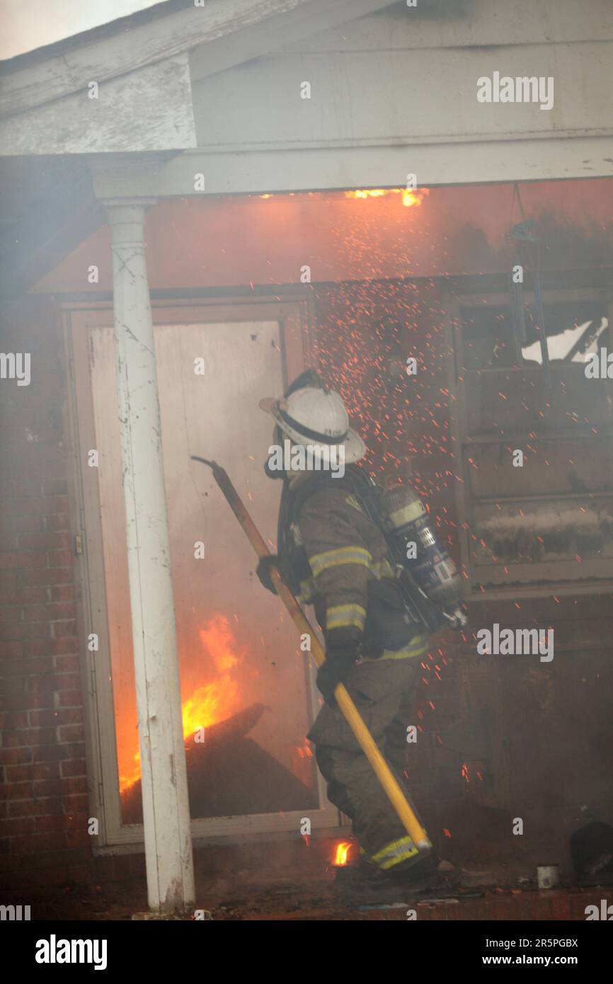 Action shot with motion-blur of firefighter working against house fire ...