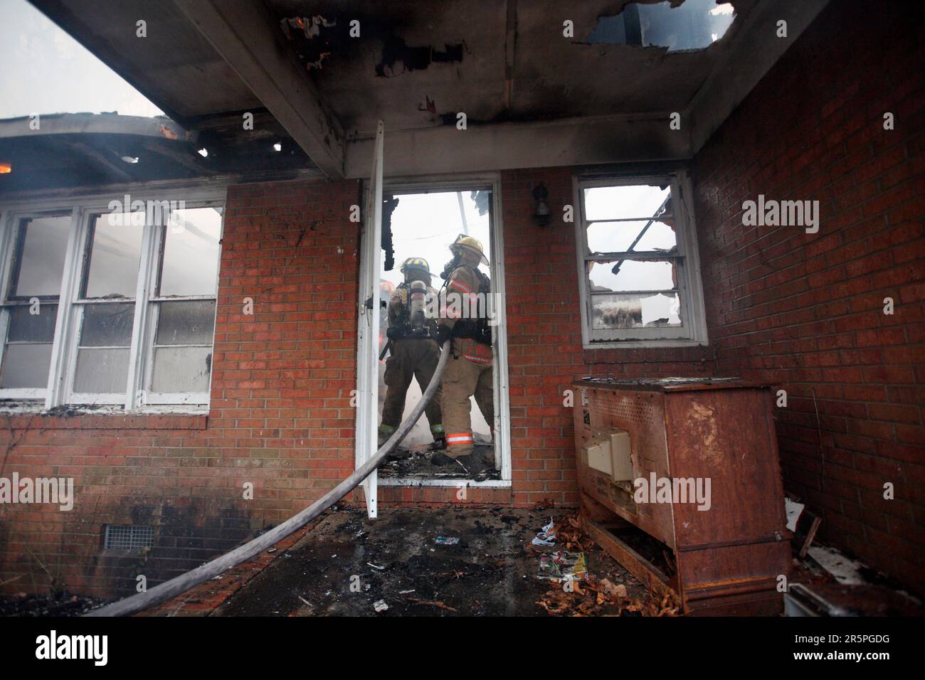 Firefighters extinguishing house fire Stock Photo - Alamy