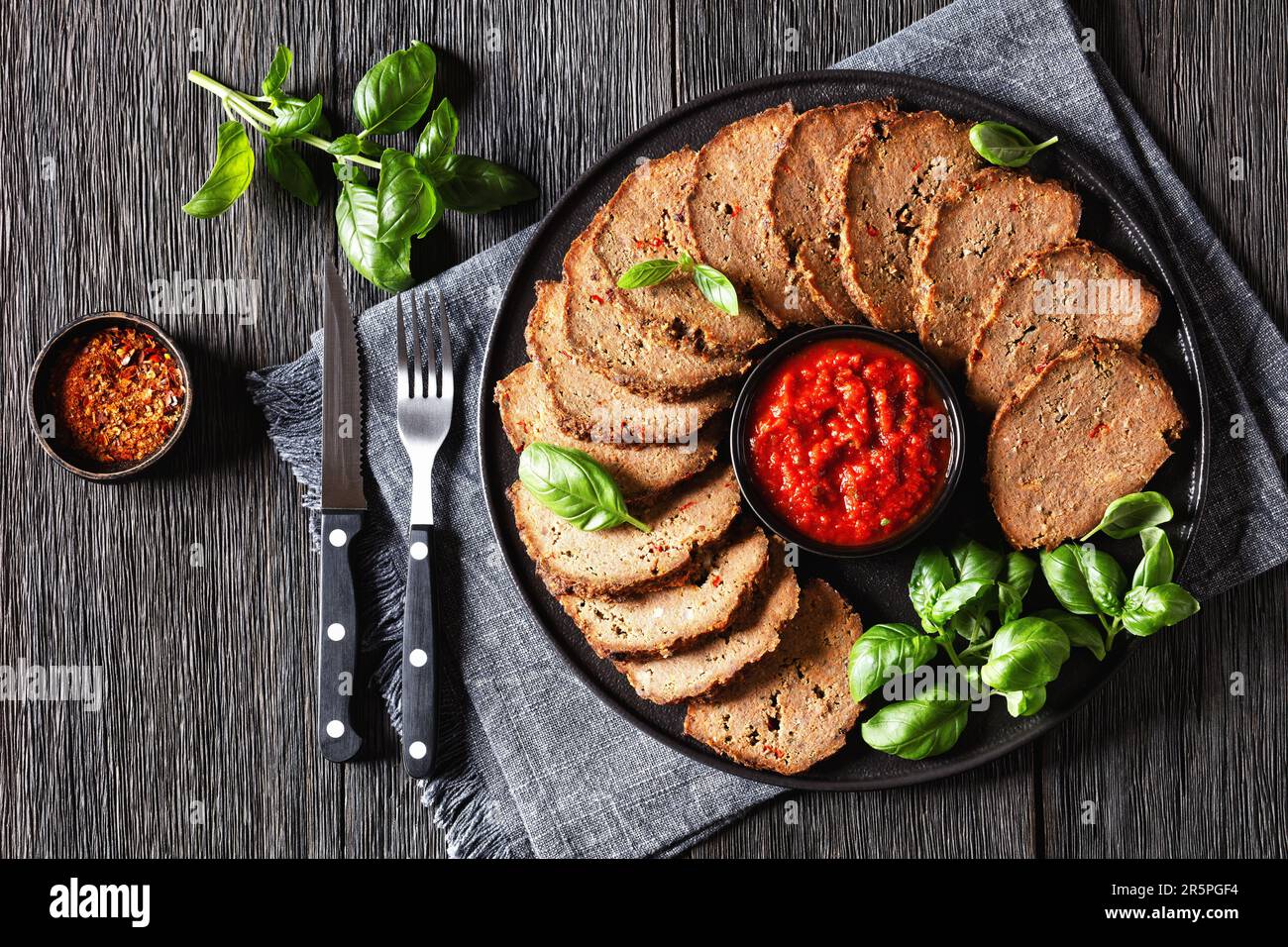 italian style meatloaf cut in slices on black platter on dark wood ...