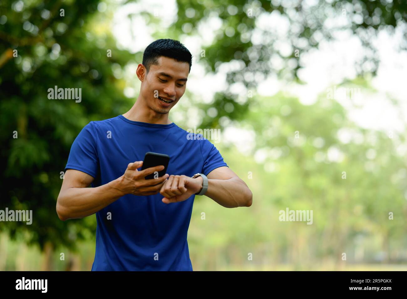 Handsome male athlete checking training program on smartphone ...