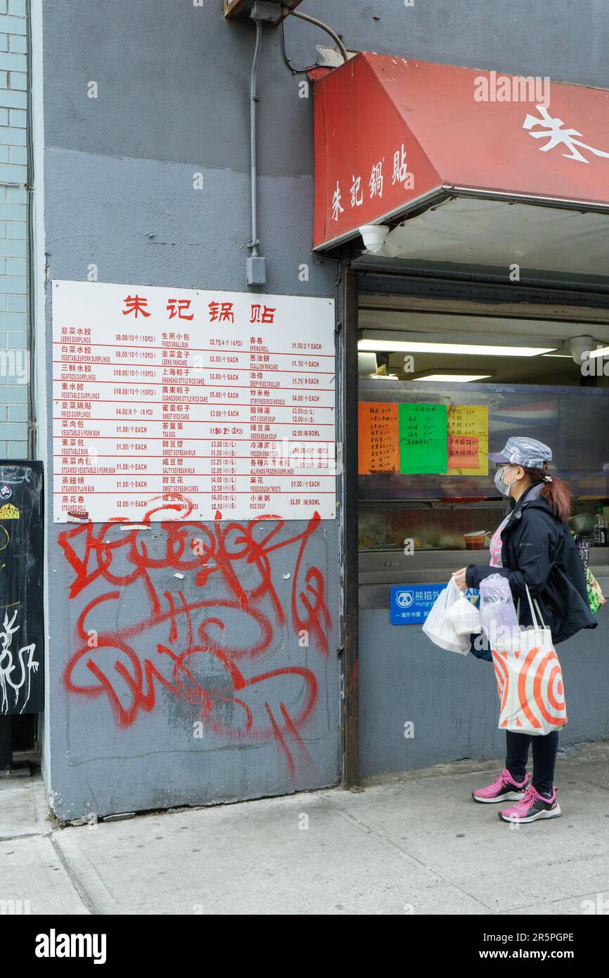 A Chinese woman wearing a mask browses a menu at a restaurant in ...