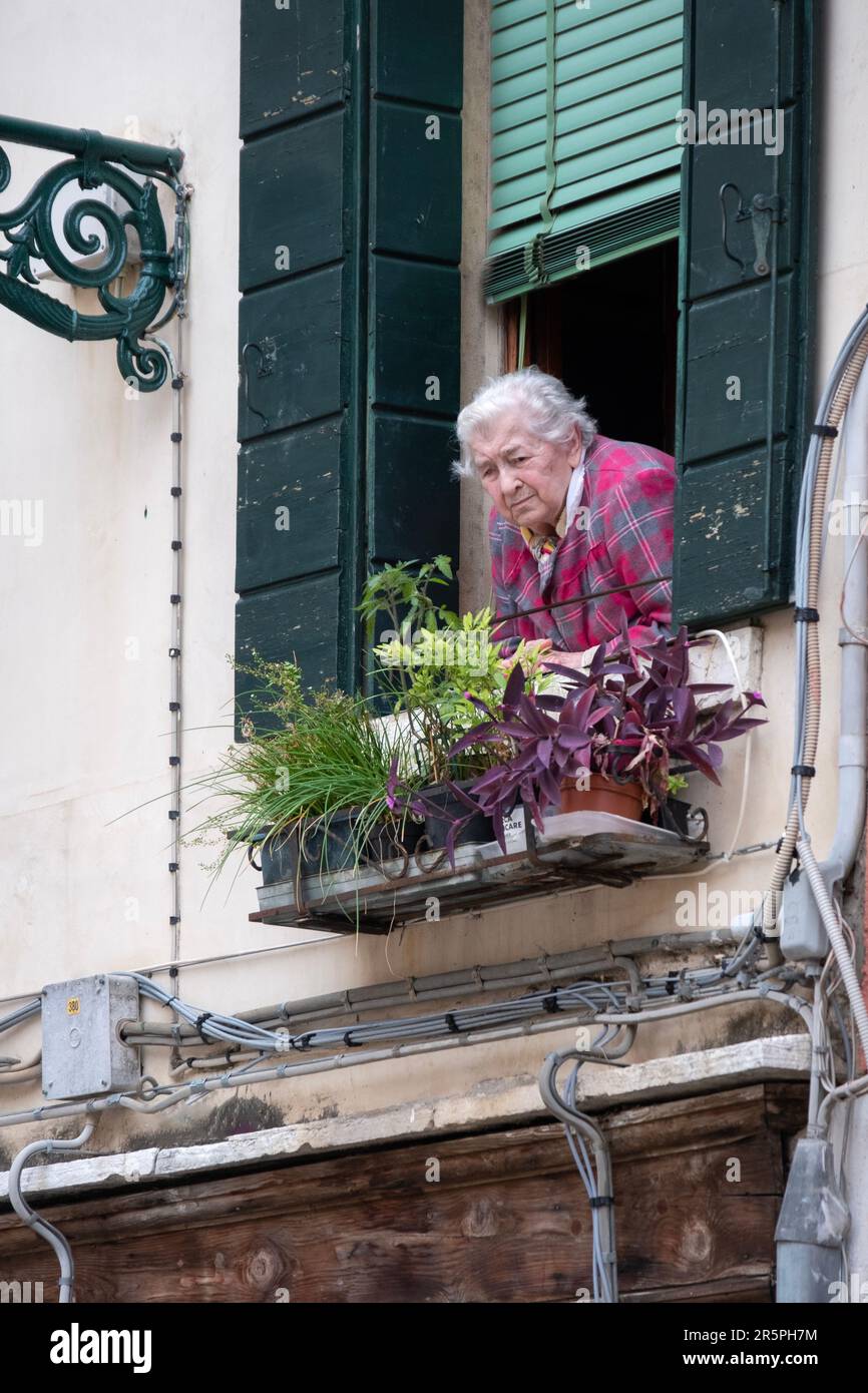 An older Venetian women deep in thought as she gazes out of her window ...