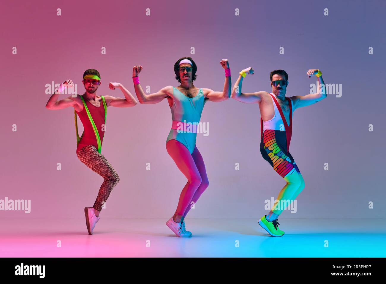 Sport show. Three funny men in colorful sportswear doing aerobics ...