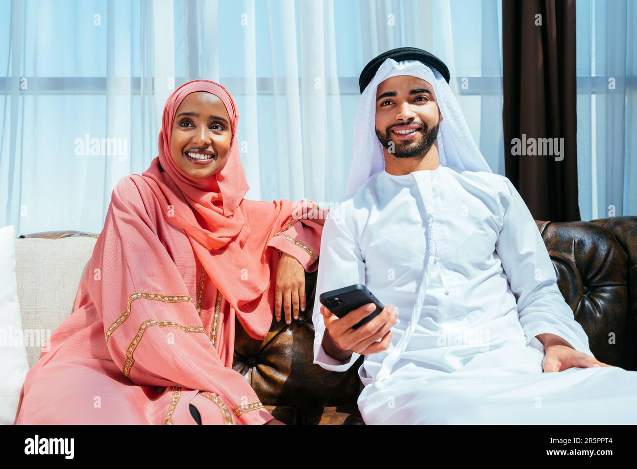 Happy middle-eastern couple wearing traditional arab clothing at home ...