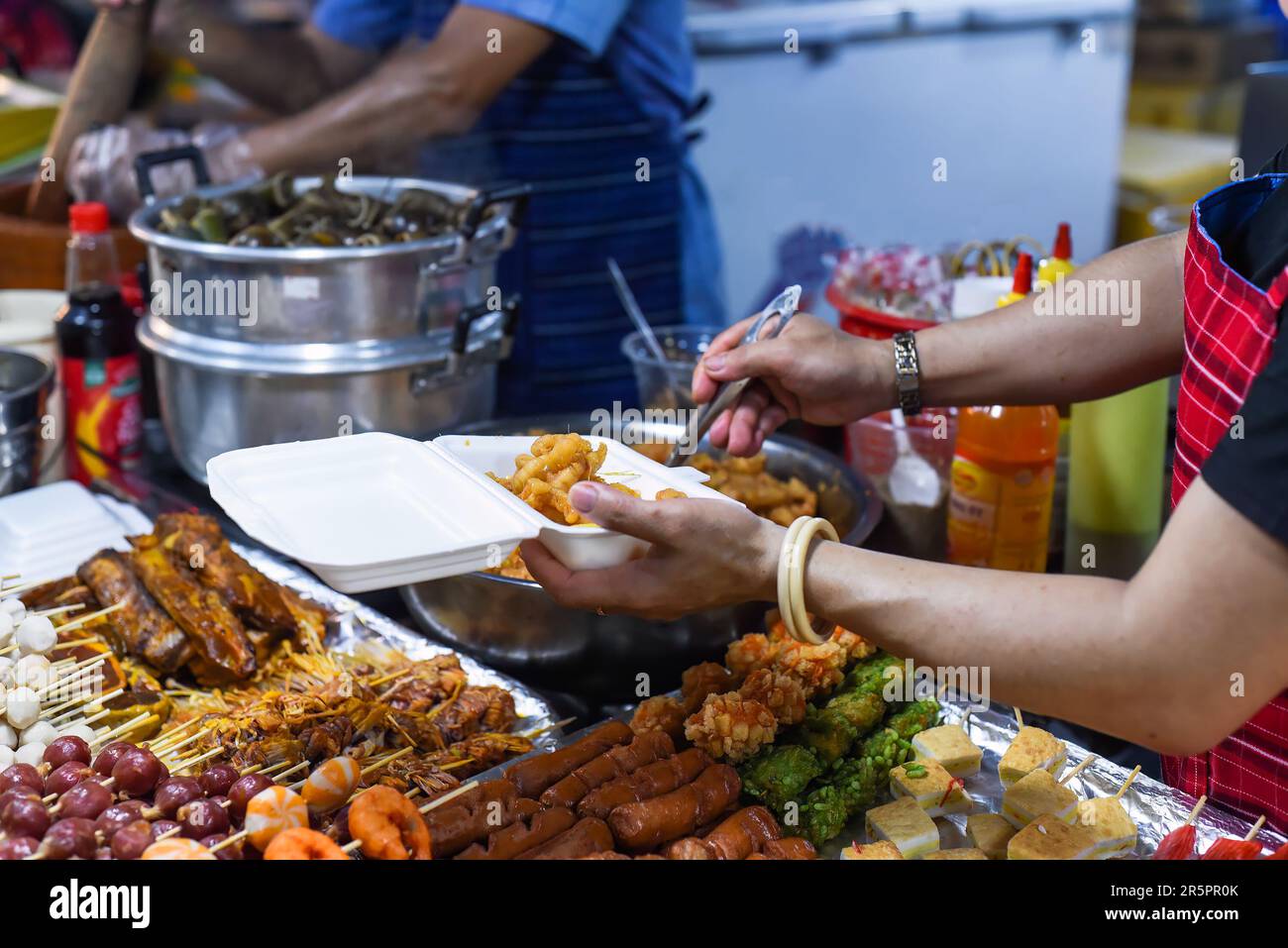 Vietnamese woman serving chicken paws in plastic box with chili in ...