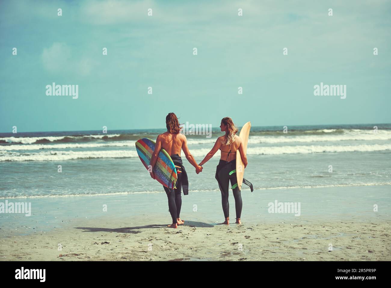 Our love will make it through rough waters. a young couple walking on the beach with their ...