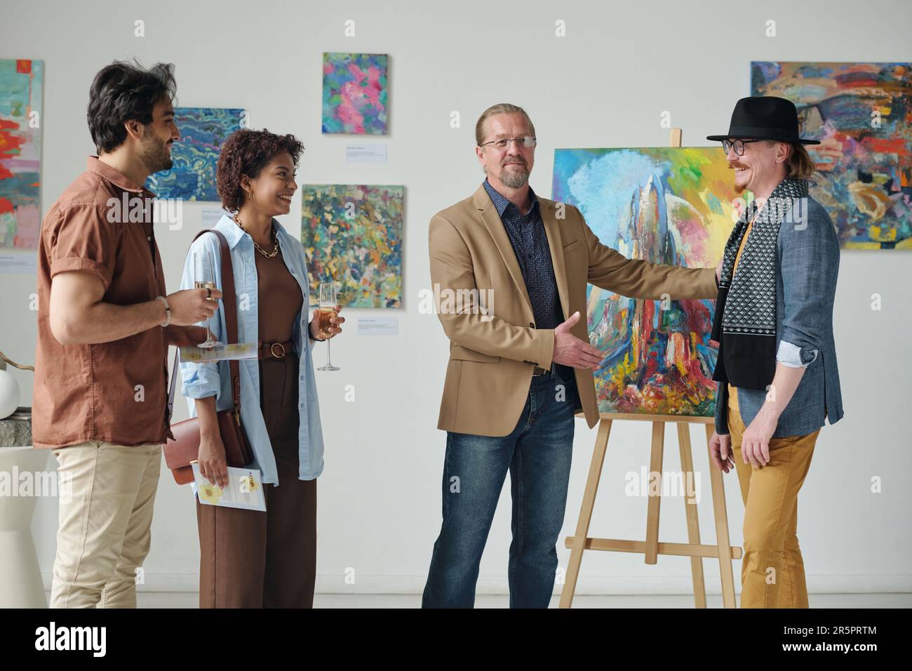 Gallery owner presenting artist of art gallery to group of people ...