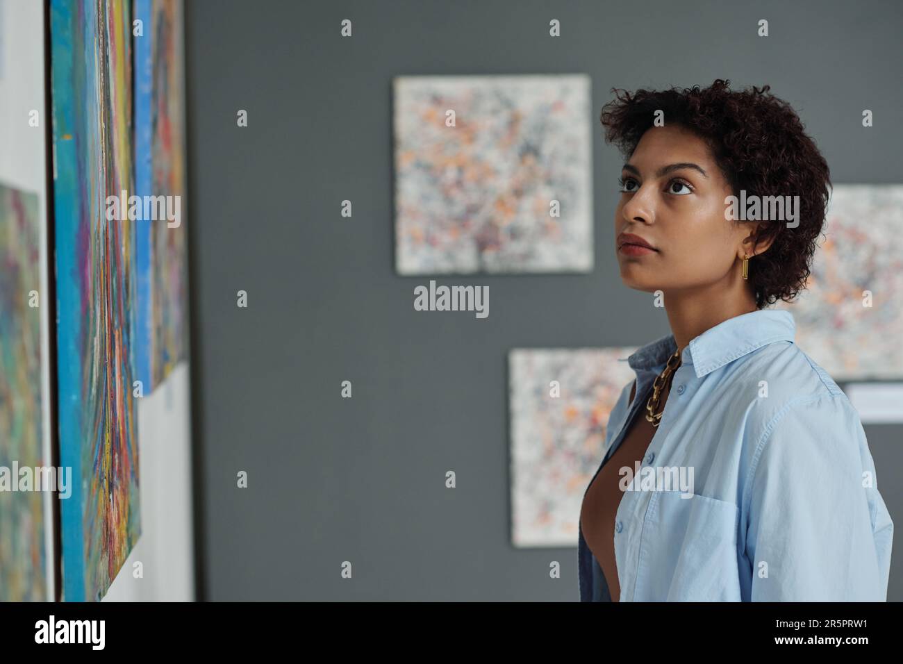 Young woman enjoying the modern art, she examining paintings on the ...