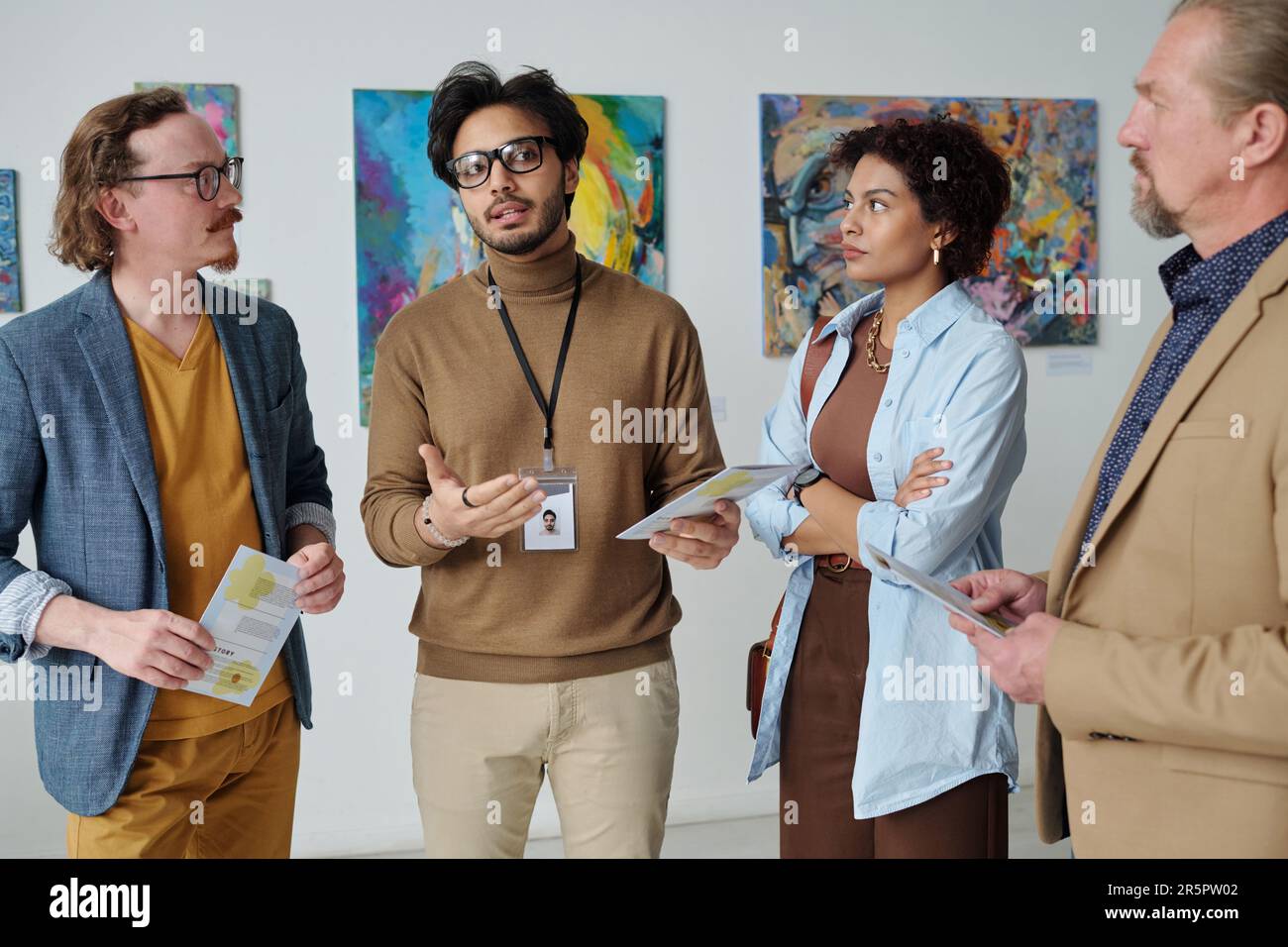 Owner of gallery talking about art to group of people during exhibition ...